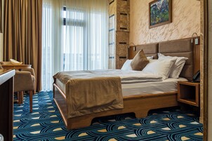 Quarto de hotel com uma cama, uma escrivaninha e uma cadeira.
