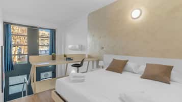 Quarto de hotel moderno com uma cama, uma escrivaninha e vista para o exterior.