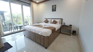 Quarto com cama de madeira, mesa de cabeceira, lixeira pequena e vista para a varanda.