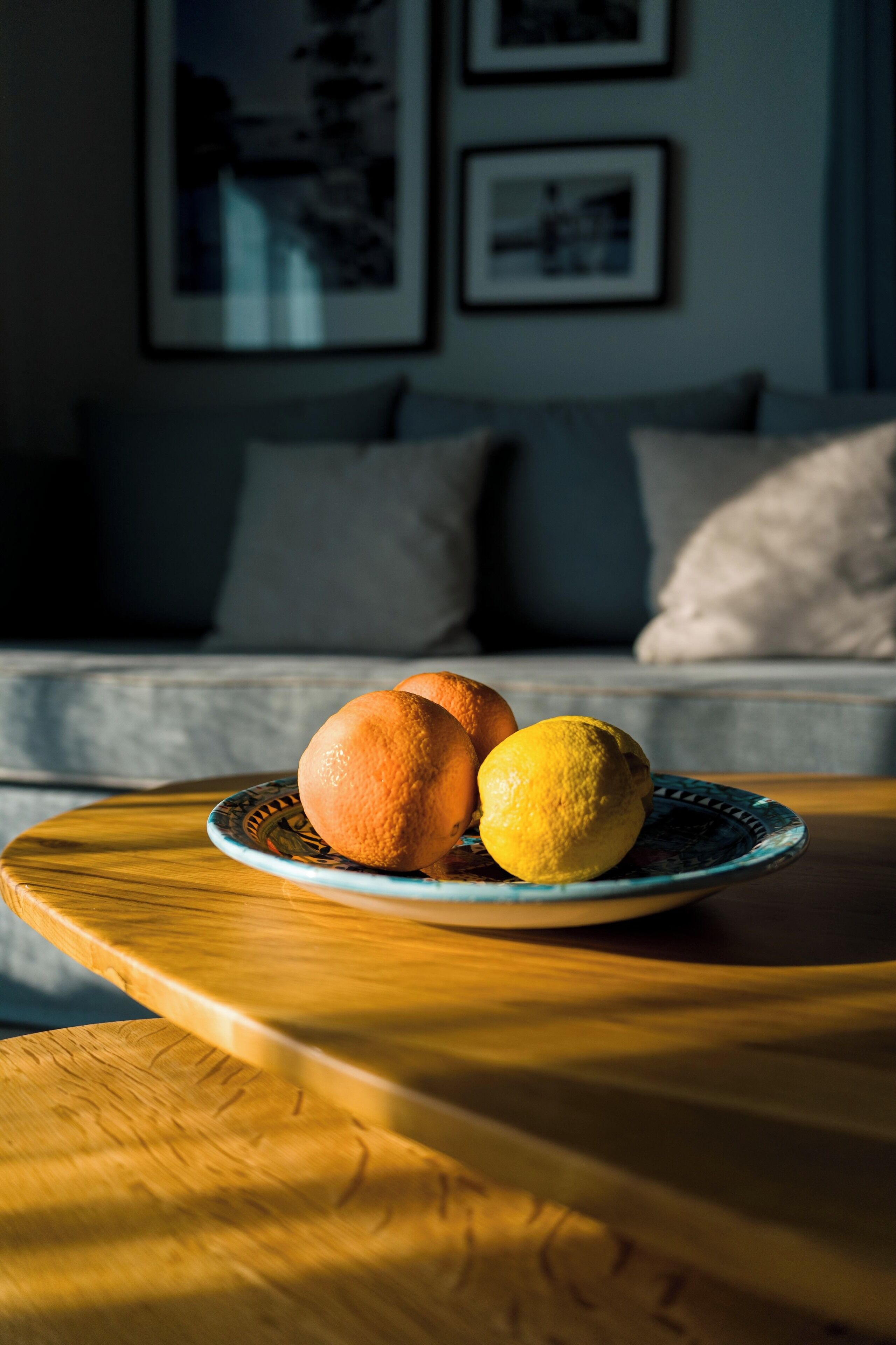 Uma mesa com um prato de laranjas e um limão.