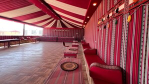 Um quarto com um sofá vermelho grande, piso de madeira e paredes com padrão.