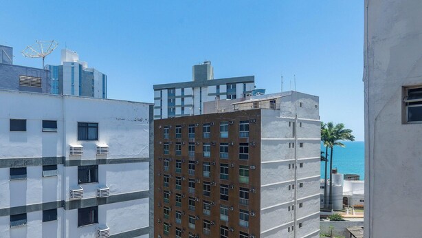 Um edifício com vários andares, combinando diferentes estilos arquitetônicos, incluindo uma estrutura moderna de vidro e um edifício tradicional de tijolo.