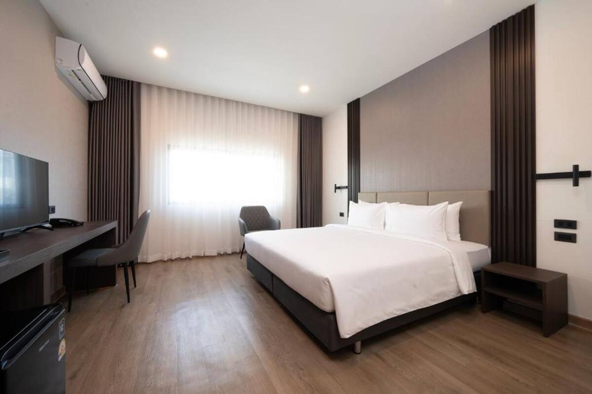 Quarto de hotel com uma cama, uma mesa com cadeira, televisão e ar condicionado.