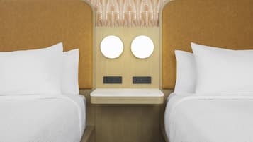 Quarto de hotel com duas camas, uma mesa de cabeceira e luminária fixada na parede.