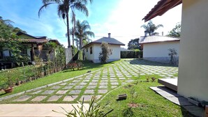 Um pátio com um caminho de pedra, um pequeno jardim e um edifício branco com telhado escuro.