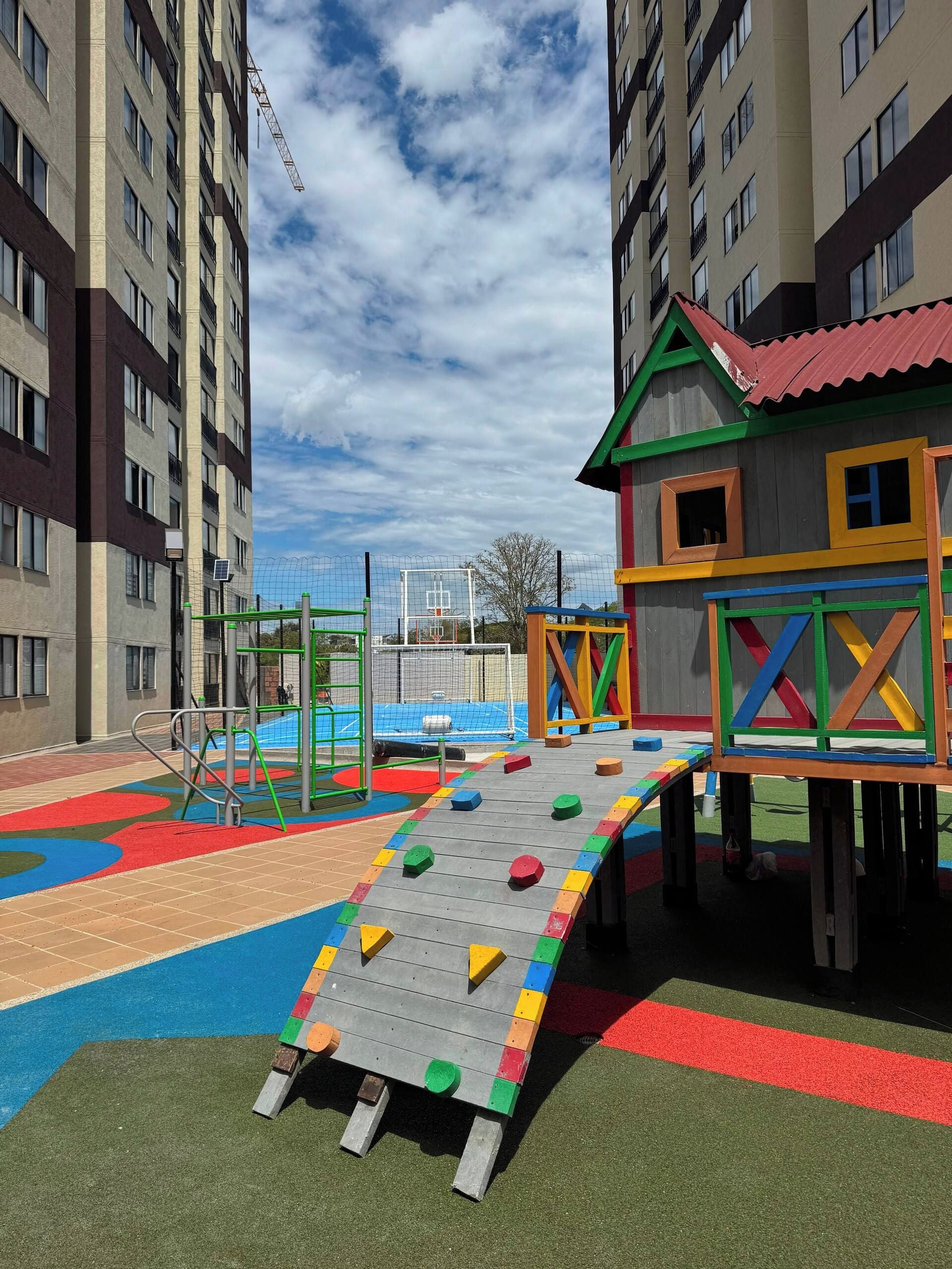 Um parquinho com brinquedos coloridos e quadra esportiva.