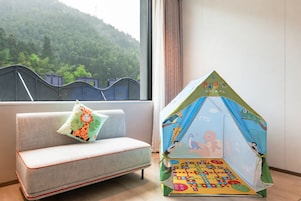 Quarto com sofá e uma tenda infantil decorada com desenhos de animais.