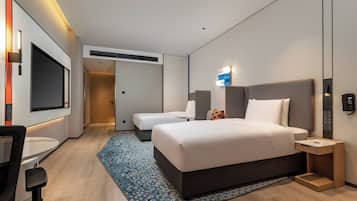 Quarto de hotel moderno com cama grande, escrivaninha, televisão e um pequeno espaço de estar.
