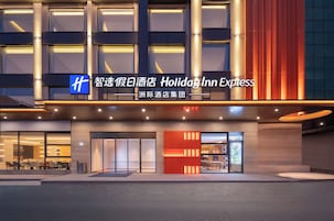 Exterior moderno de hotel com a placa Holiday Inn Express, janelas amplas e entrada bem iluminada.