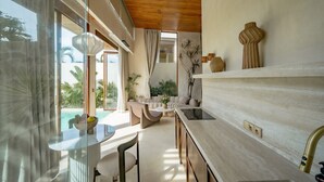 Uma cozinha moderna com uma ilha grande, uma área de jantar com mesa de vidro e vista para uma piscina.