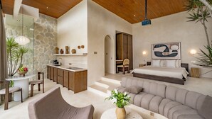 Interior moderno com cozinha, sala de jantar e quarto com cama grande e obras de arte.