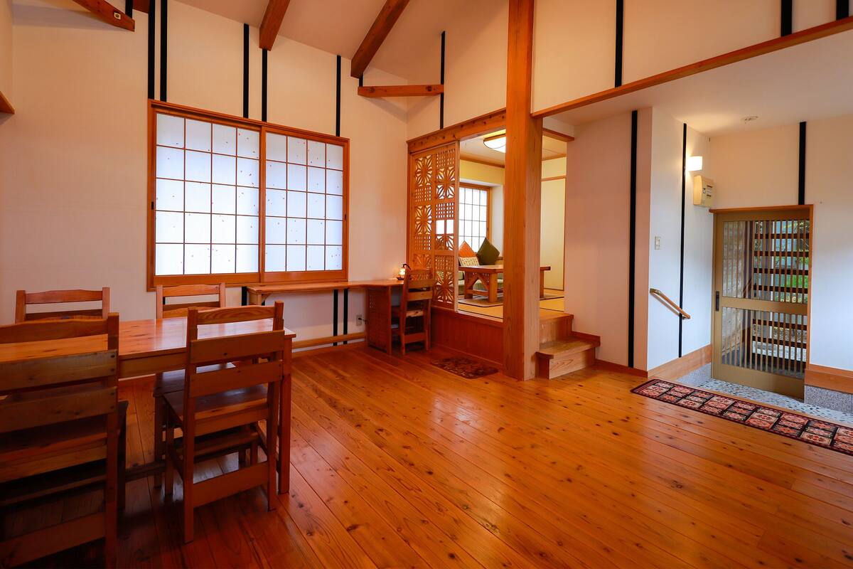 Um quarto japonês tradicional com tatames, um painel shoji e uma mesa de madeira com cadeiras.