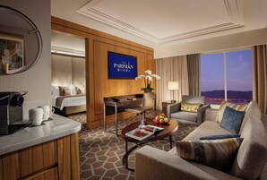Quarto de hotel com cama, escrivaninha, sofá, máquina de café e vista para a cidade.