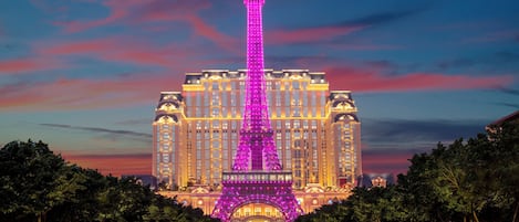 Um hotel grande com uma torre imponente que lembra a Torre Eiffel, rodeado por um gramado bem cuidado e árvores.