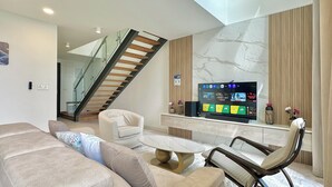Uma sala de estar moderna com sofá, mesa de centro, televisão e escada.