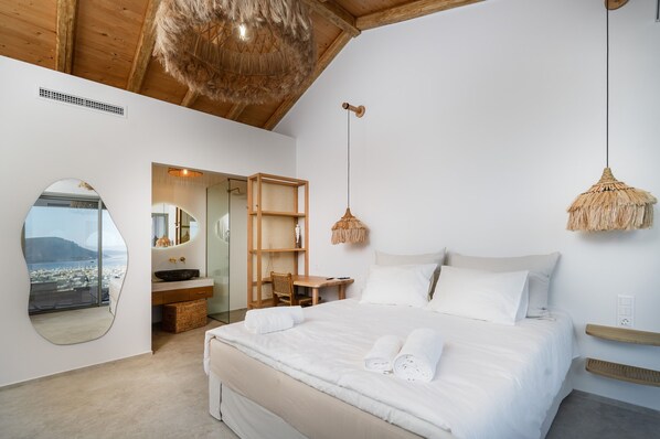 Quarto moderno com cama grande, espelho, teto de madeira e vista para a cidade.