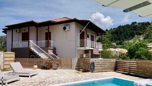 Uma casa de dois andares com piscina, mobiliário de exterior e escadaria que dá acesso ao andar superior.