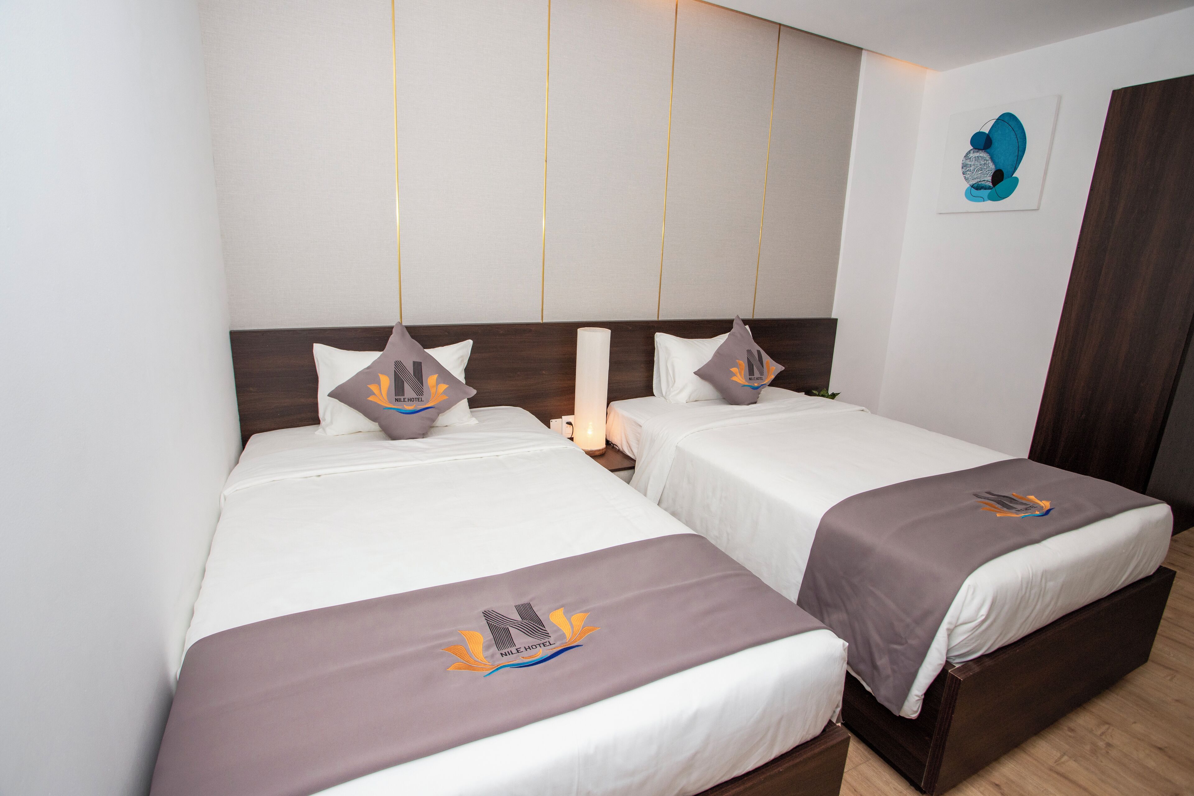 Quarto de hotel com duas camas, cada uma com cabeceira marrom e roupa de cama branca.