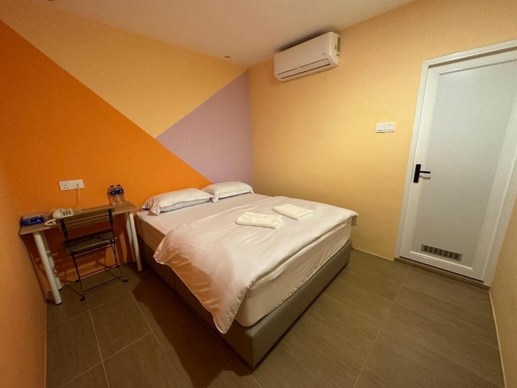 Um quarto com uma cama, uma mesa de cabeceira com abajur, ar condicionado e uma porta.