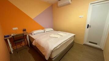 Um quarto com uma cama, uma mesa de cabeceira com abajur, ar condicionado e uma porta.