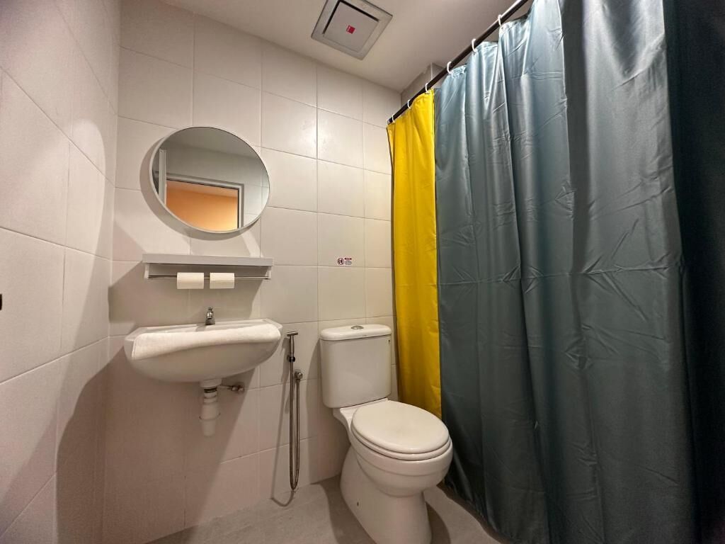 Casa de banho com lavatório branco, sanita e cortina de chuveiro.