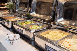 Buffet com diversas opções de comida, incluindo saladas, arroz e milho.