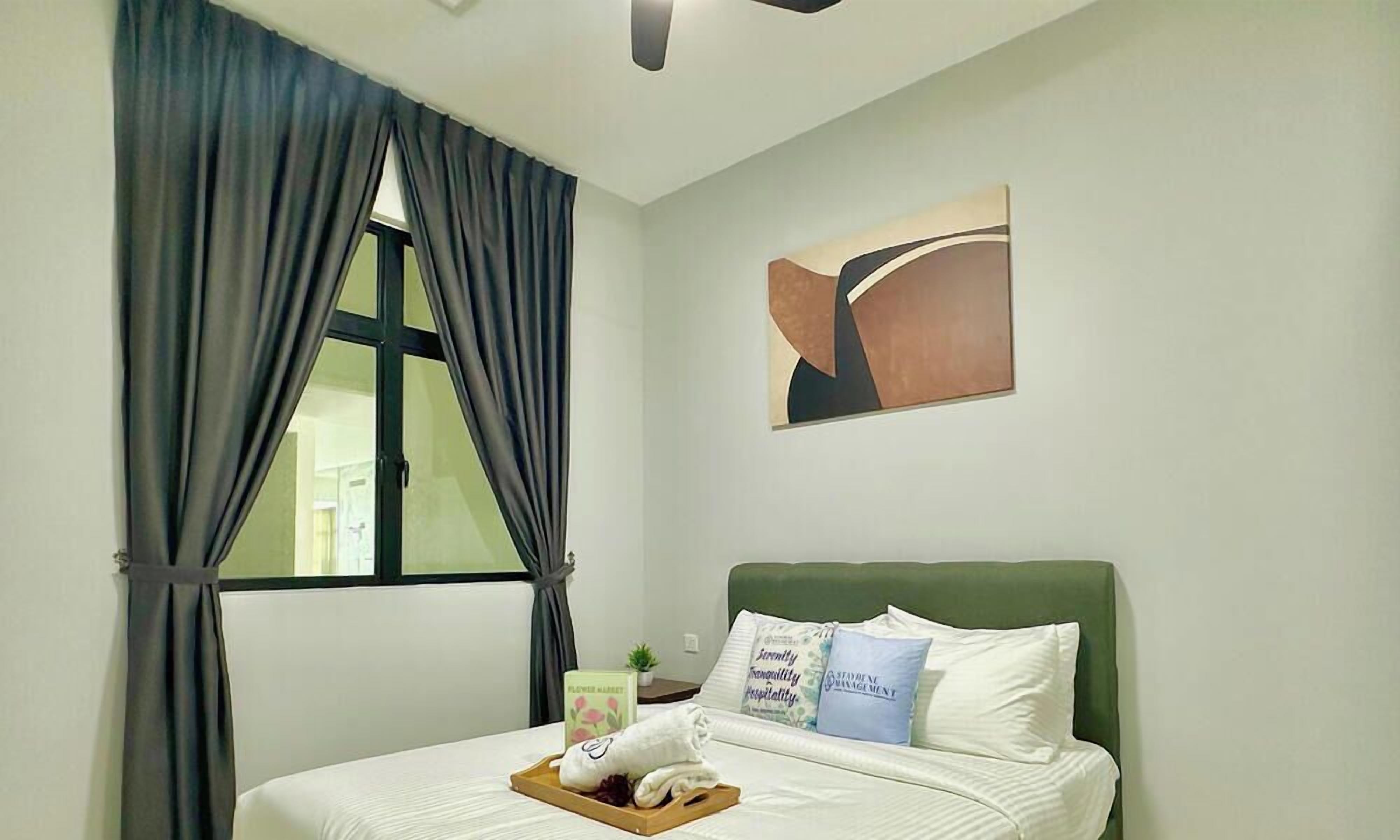 Quarto de hotel com cama, janela com cortinas, uma obra de arte na parede e um tabuleiro com toalhas sobre a cama.