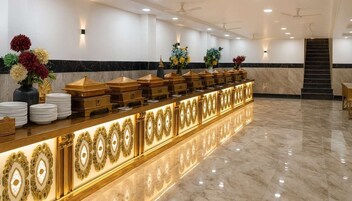 Uma área de recepção com piso de mármore, um balcão de atendimento com detalhes dourados e uma escadaria ao fundo.