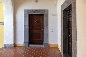 Um corredor com porta de madeira, piso de azulejos e parede de pedra.