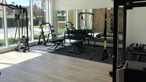 Uma academia moderna com diversos equipamentos de exercícios, janelas amplas e vista para o exterior.