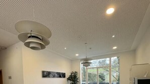 Um interior moderno com teto com padrão perfurado, iluminação embutida e uma janela ampla que oferece luz natural.