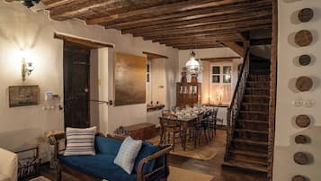 Um interior rústico com vigas de madeira aparentes, uma área de jantar e uma escada.