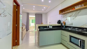 Uma cozinha moderna com bancada preta, eletrodomésticos de aço inoxidável e painel de fundo de mármore.