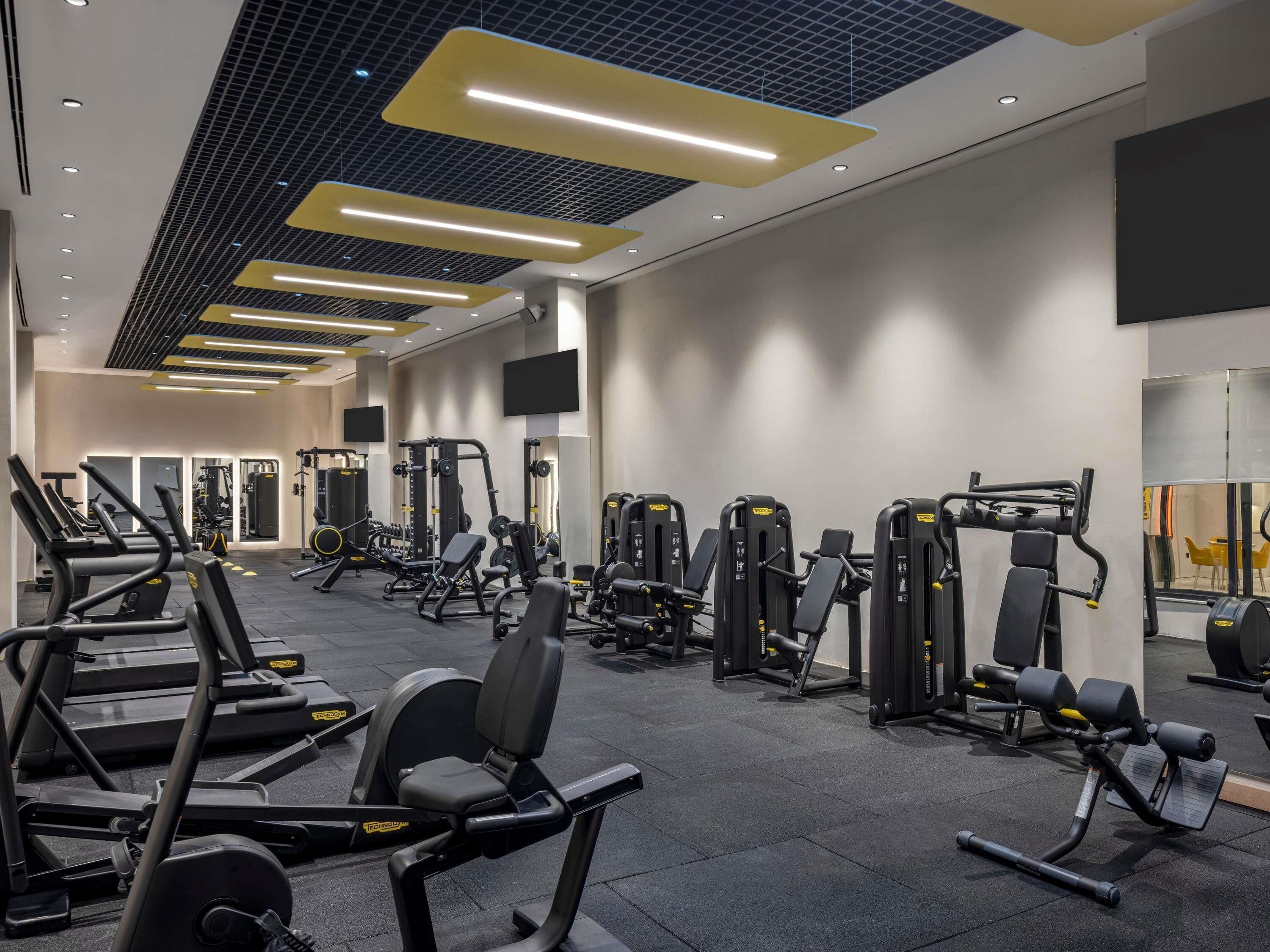 Uma academia moderna com diversos equipamentos de ginástica, um espelho grande e um interior limpo e bem iluminado.