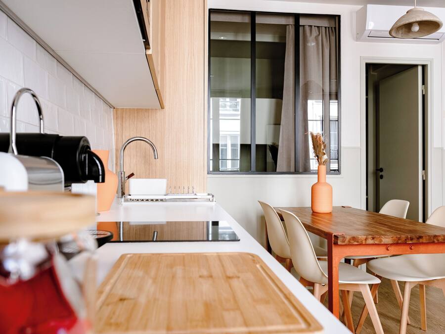 Uma cozinha moderna com bancada de madeira, forno embutido, pia e um espaço de refeições com mesa e cadeiras de madeira.