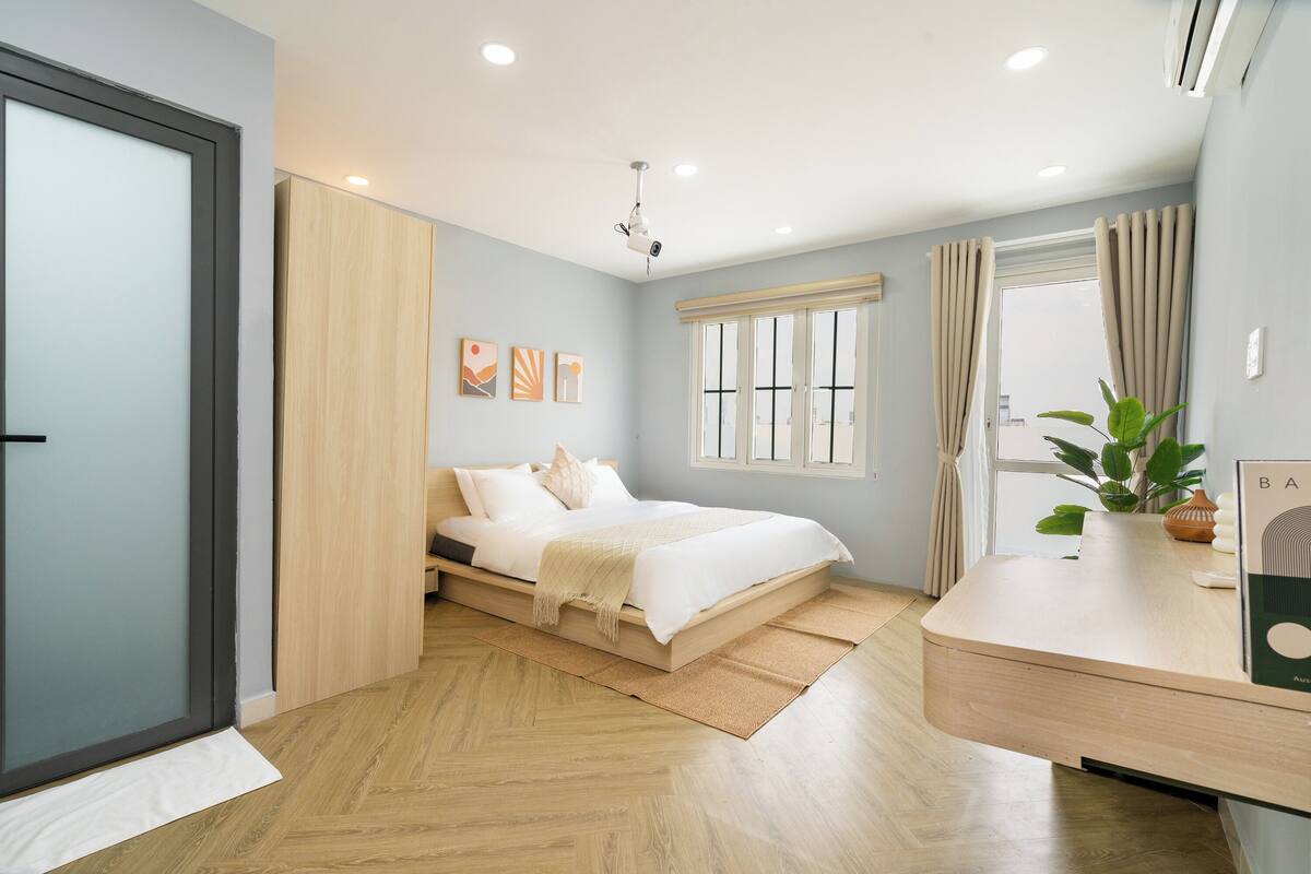 Quarto moderno com cama, mesa de cabeceira e janela com cortinas.