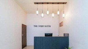 Uma mesa de recepção com uma placa indicando "THE IVORY SUITES" e uma planta em vaso à direita.
