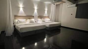 Quarto moderno com uma cama grande, duas mesas de cabeceira e um ventilador de teto.