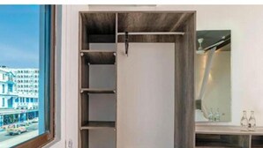 Quarto de hotel moderno com um guarda-roupa espaçoso, um espelho e vista para a cidade.
