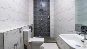 Uma casa de banho compacta com sanita, chuveiro e lavatório.