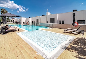Área de piscina no terraço com piscina azul cristalina, espreguiçadeiras e um salva-vidas.
