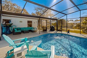 Área da piscina com estrutura de vidro, assentos e vista para o exterior.