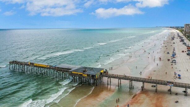 Um cais se estendendo para o oceano, com uma praia de um lado.