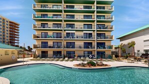 Um hotel com vários andares, varandas, piscina e áreas de estar ao ar livre.