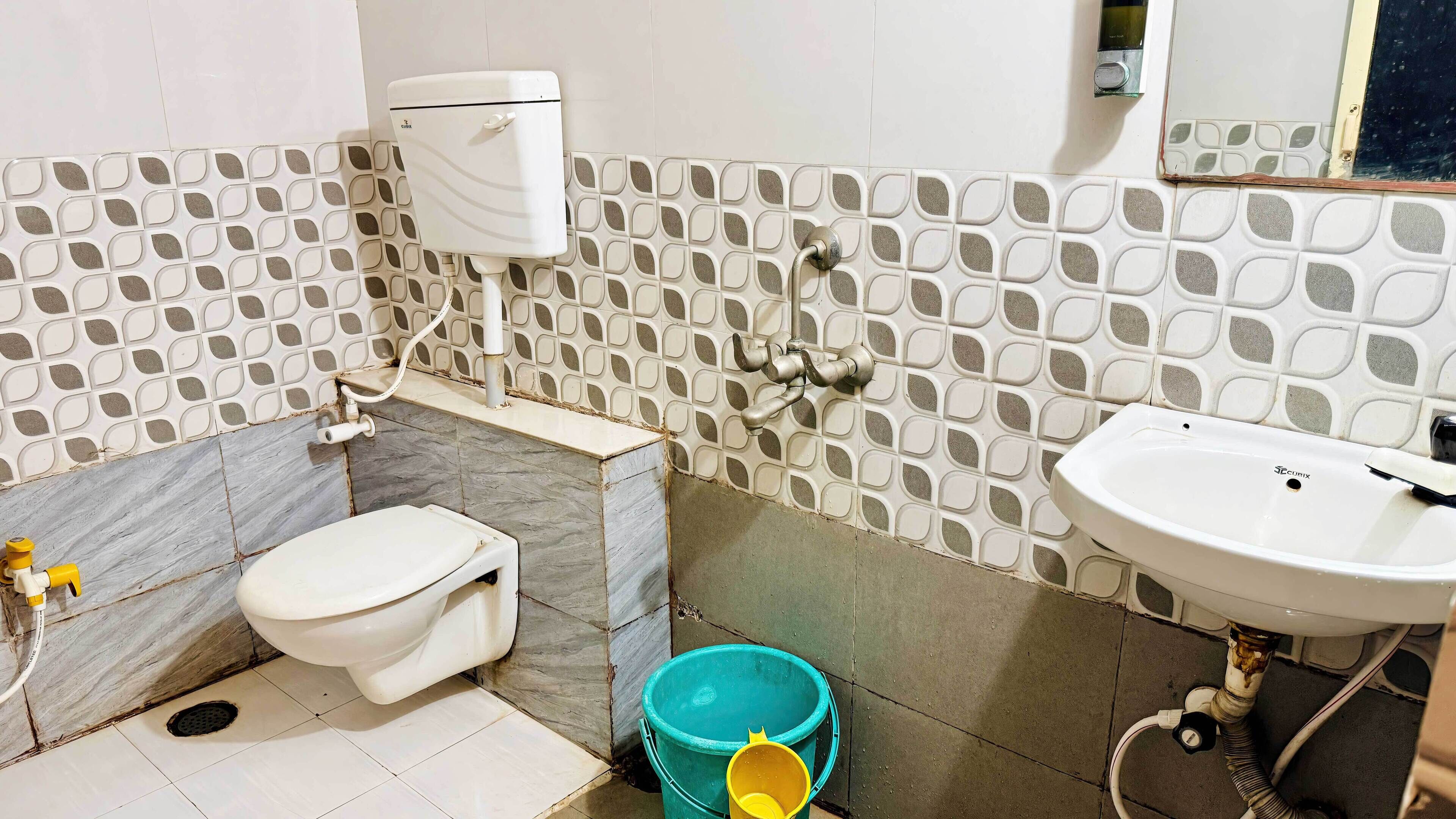 Casa de banho com sanita, lavatório e suporte para papel higiénico.