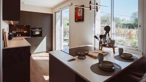 Uma cozinha moderna com uma ilha grande, eletrodomésticos embutidos e vista para o exterior.