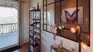 Quarto com adega, vaso com flores, decoração de borboleta e vista para o exterior.