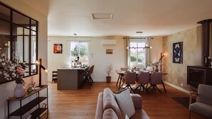 Uma sala de estar ampla com sofá, mesa de jantar, cadeiras, ilha de cozinha e lareira.