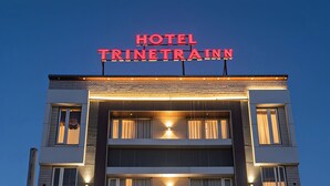 Um hotel com vários andares e uma placa de destaque com a inscrição "HOTEL TRINETRA INN".