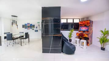 Interior moderno com coluna de mármore preto, máquina de jogos e área de jantar com cadeiras e mesa.